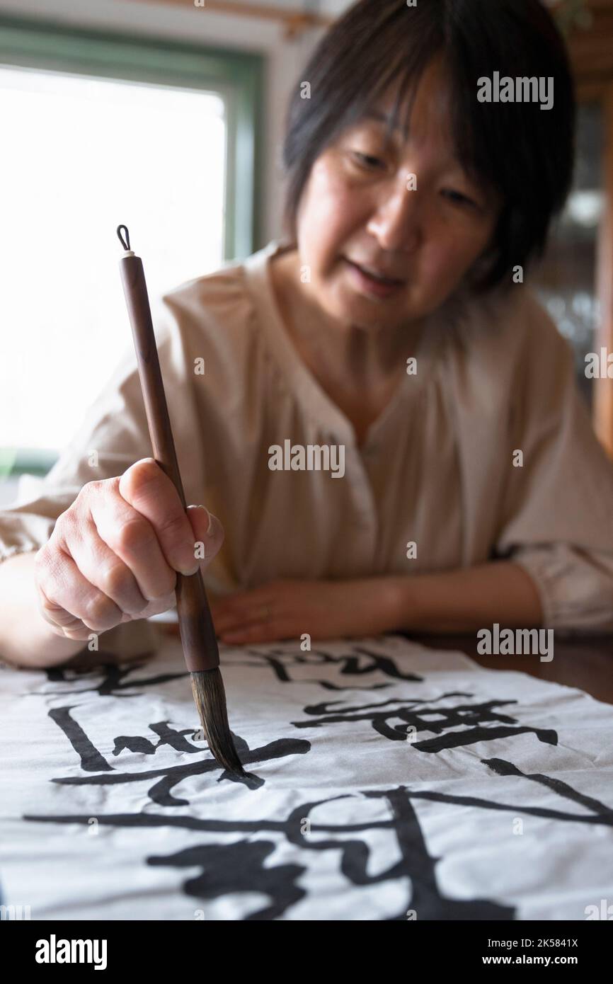 Focused female artist brush painting Japanese calligraphy Stock Photo ...