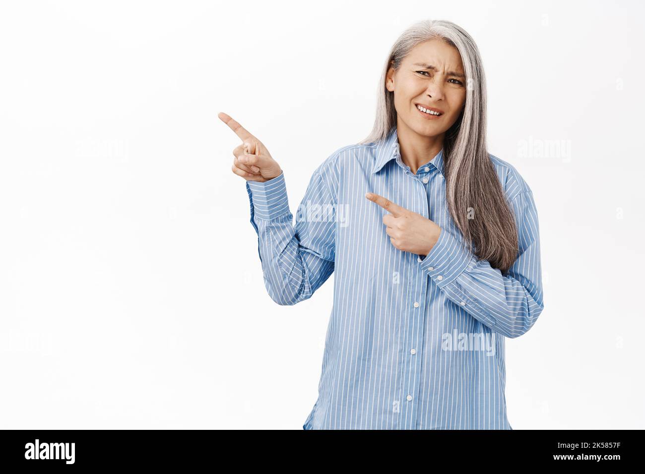 Disappointed asian senior woman, korean old lady pointing finger left ...