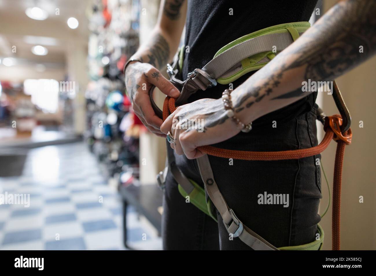 Young transgender woman preparing safety harness at climbing center ...