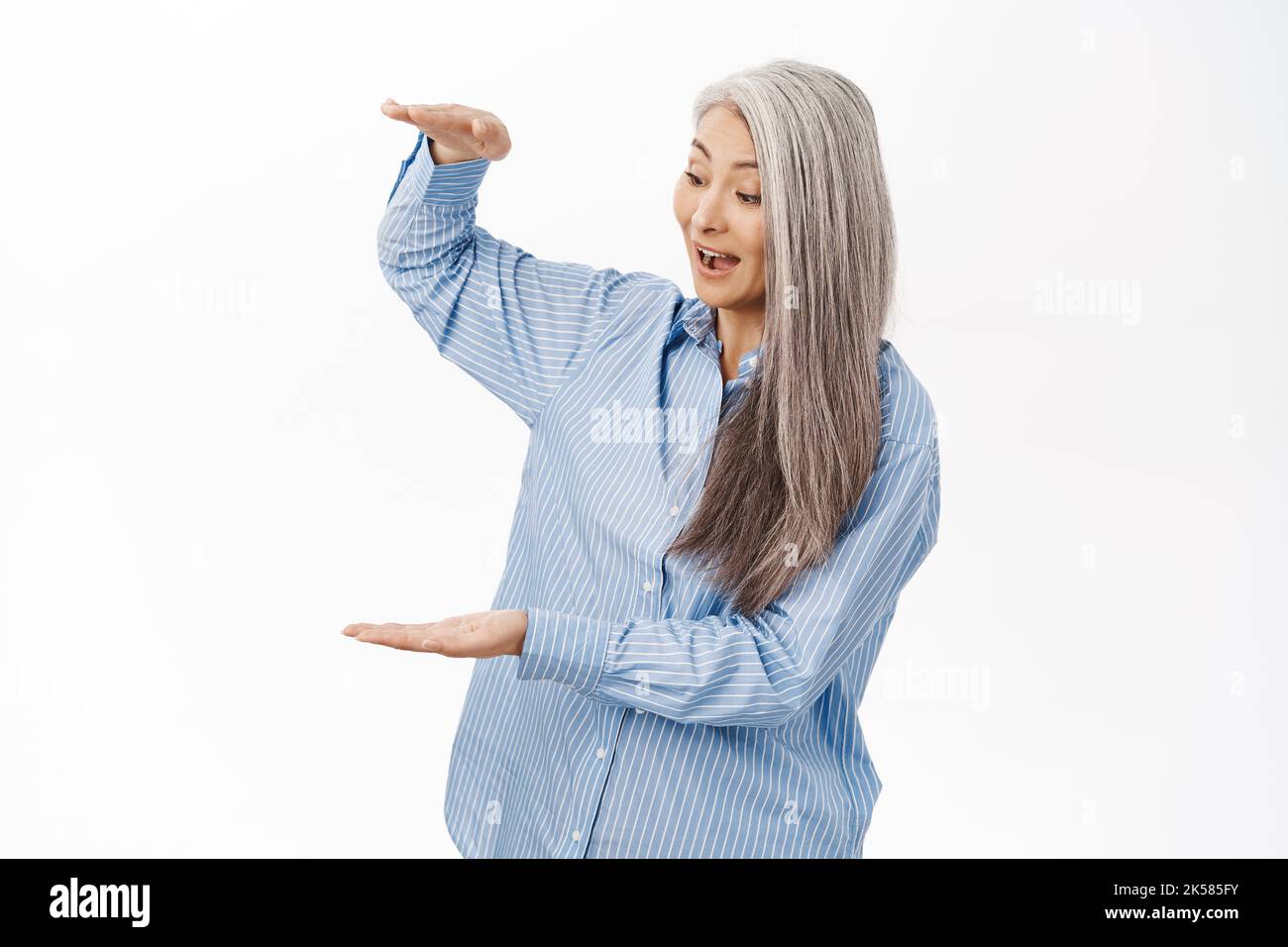 Smiling senior woman holding object, copy space between her hands ...