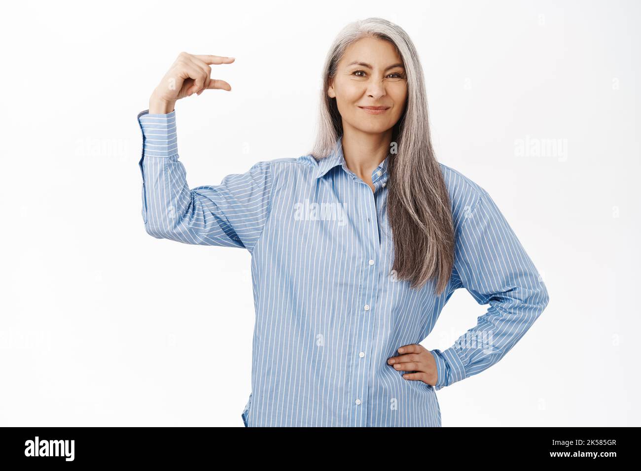 Asian senior woman with grey hair showing smth small, shaping tiny ...