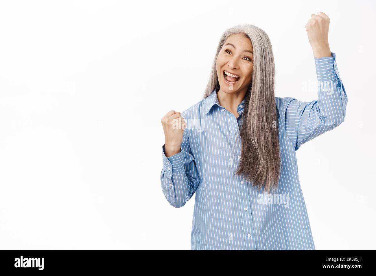 Enthusiastic senior asian woman celebrating, triumphing and shouting ...