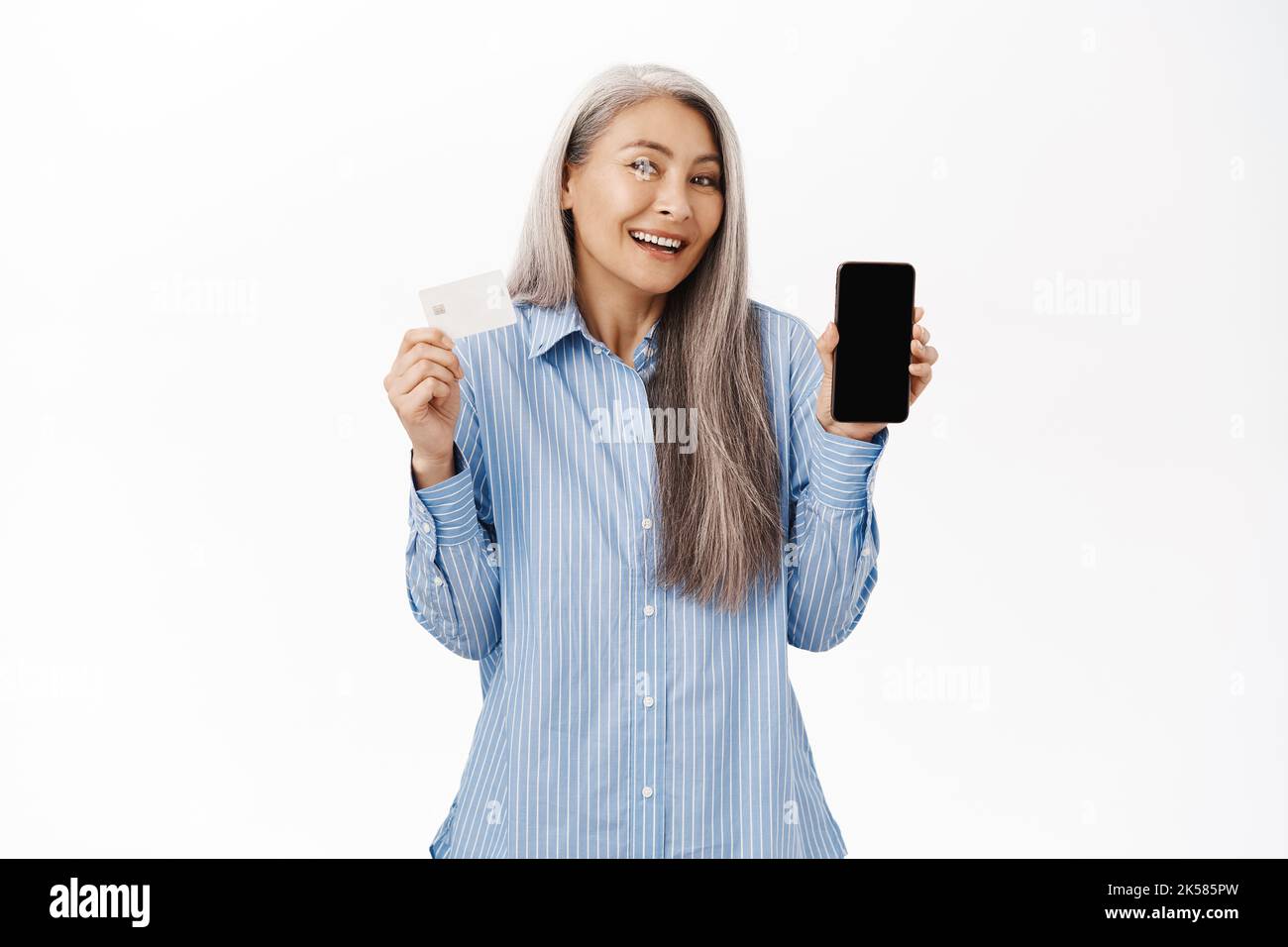 Happy korean senior woman, grandmother showing mobile phone screen and ...