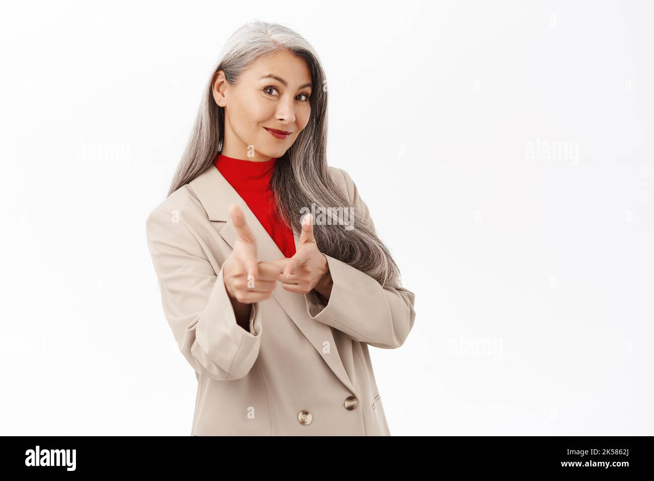 Portrait of smiling businesswoman, asian senior lady in suit, pointing ...