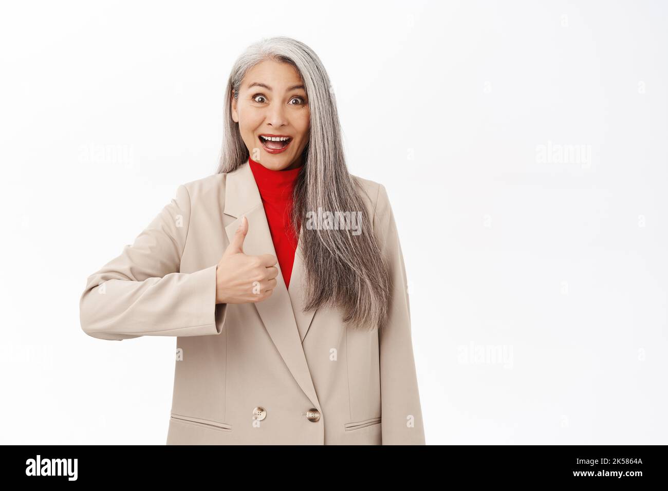 Portrait of pleased asian senior business woman, showing thumbs up ...