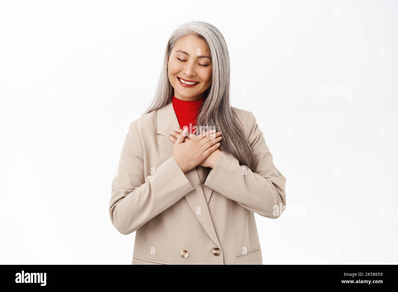 Portrait of pleased asian businesswoman, senior lady in suit looking ...