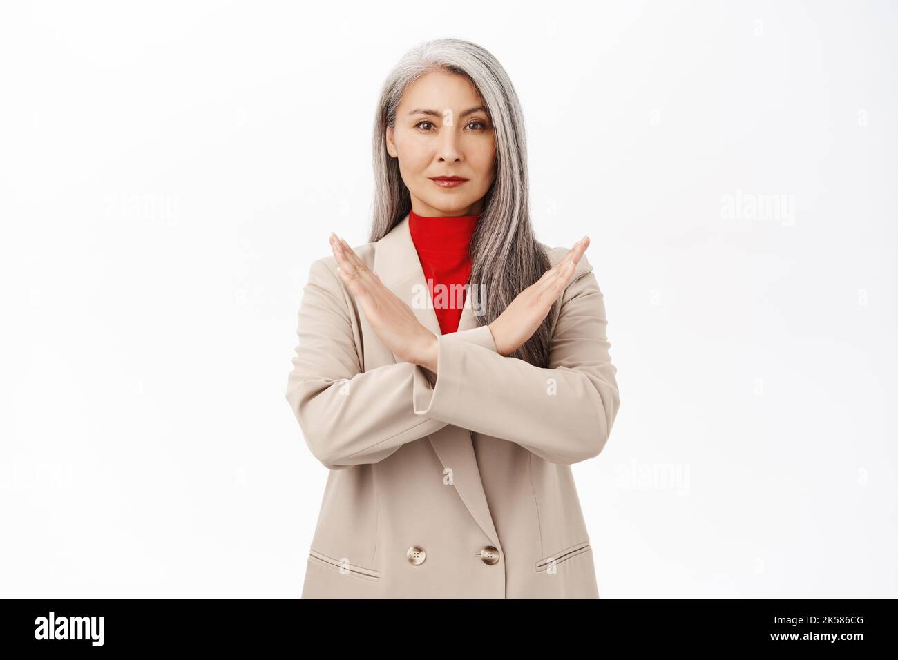 Image of serious asian lady in business clothes, showing cross, stop ...