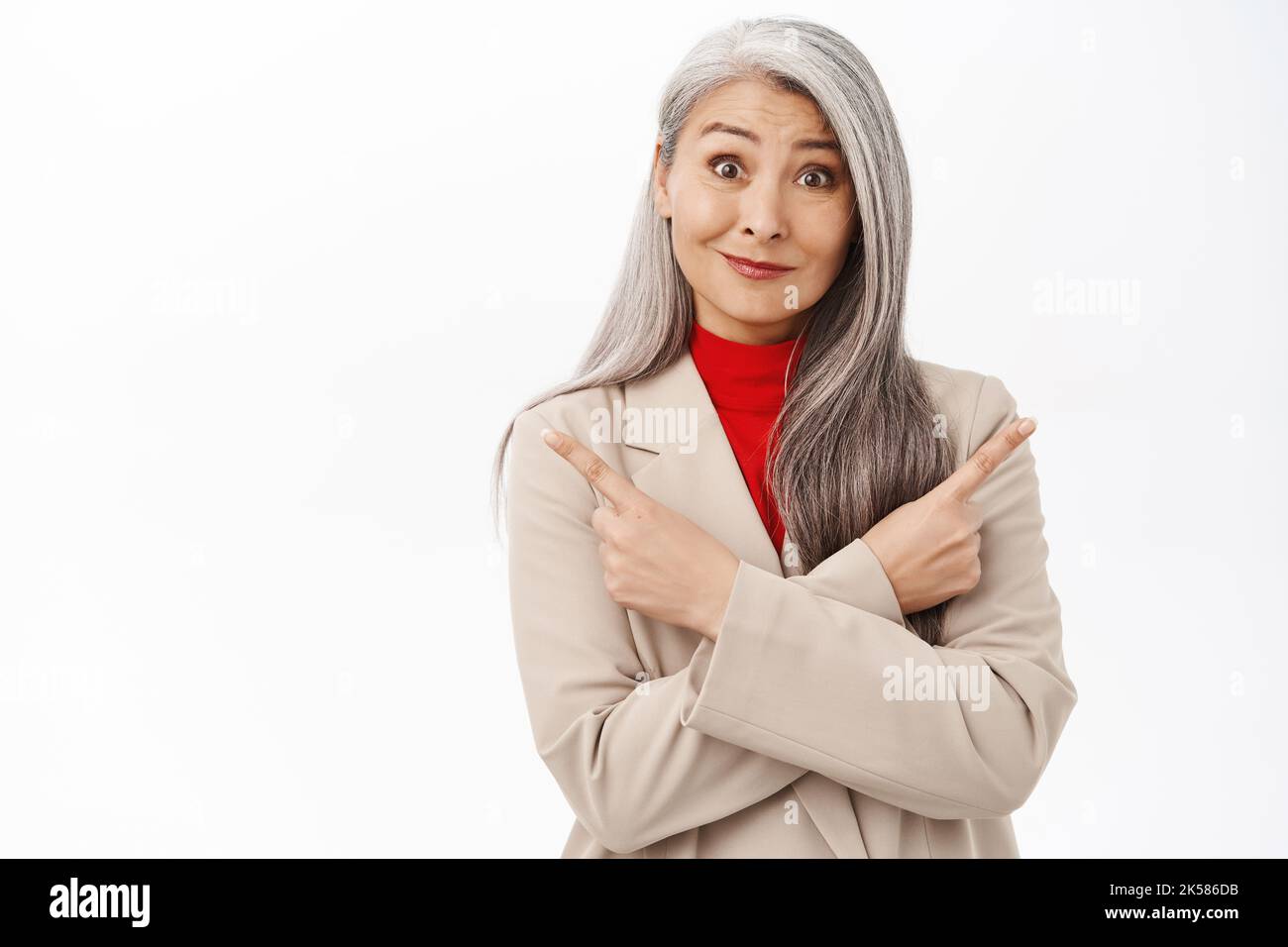 Complicated decision. Unsure asian senior woman, pointing sideways with ...