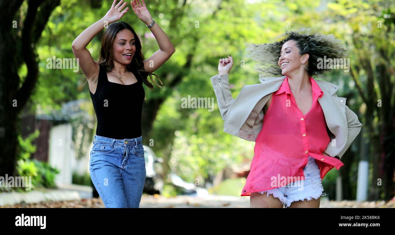 Happy people dance outside in street, two female friends celebrating ...