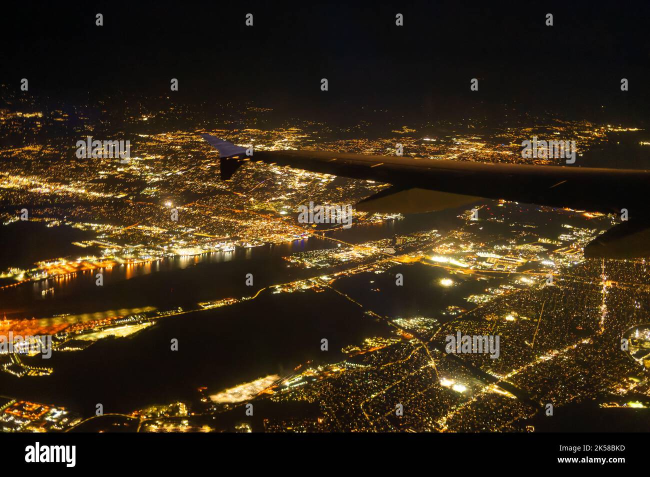 Night city in golden lights from the window of an airplane flying high ...