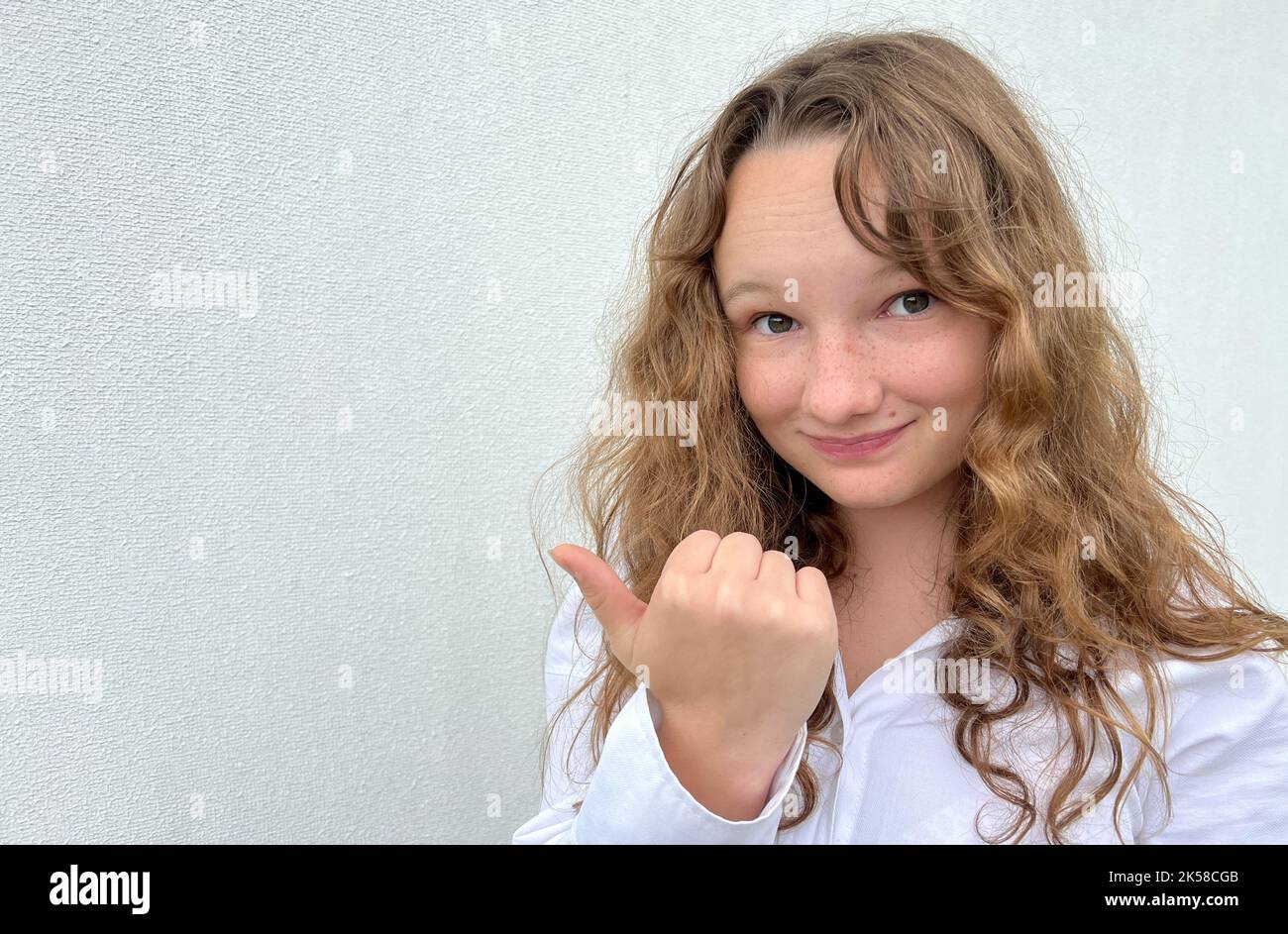 a girl on a white background in a white blouse, fair-haired, shows ...