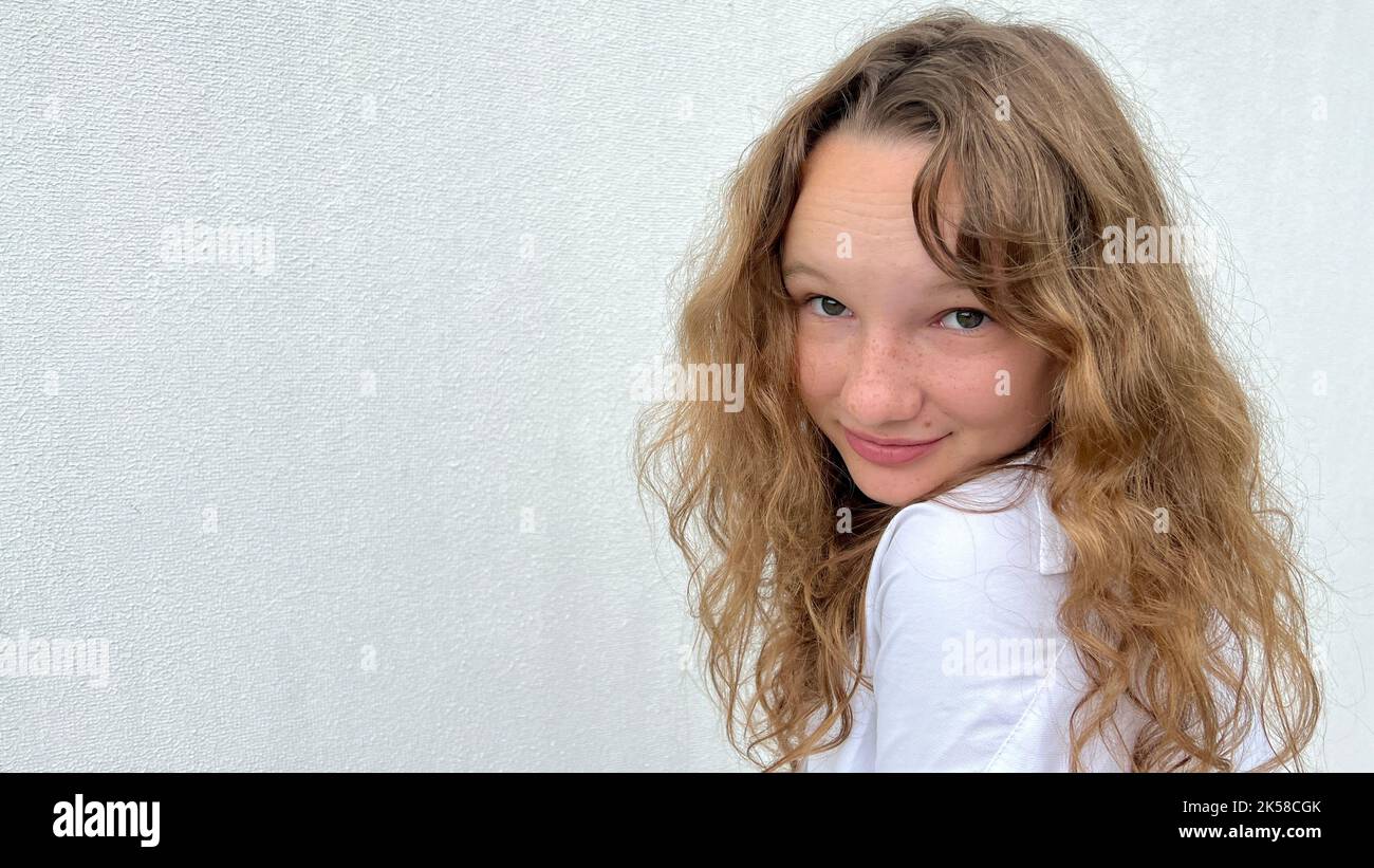 a girl on a white background in a white blouse, fair-haired, shows ...