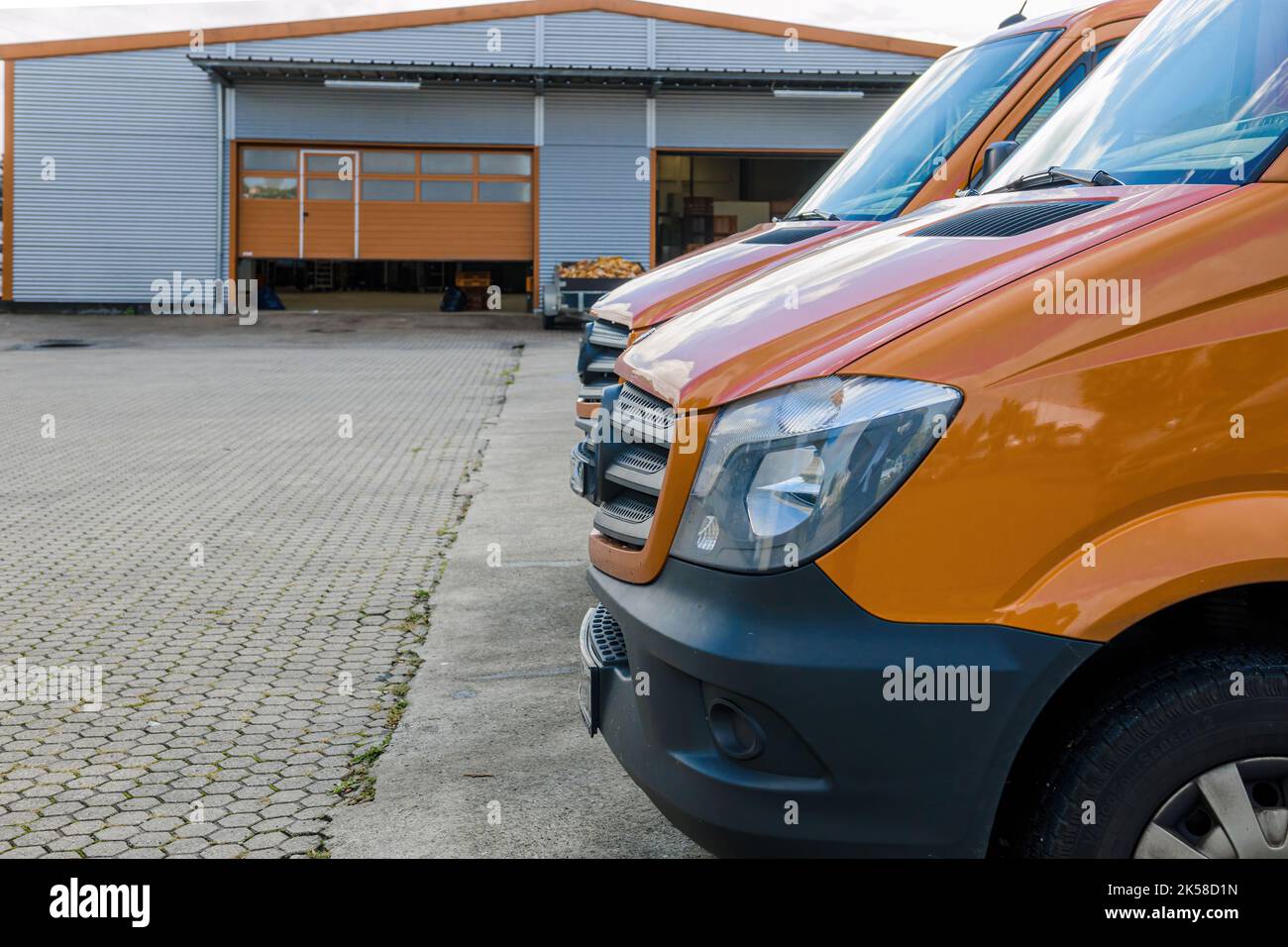 Front part of a row of two orange delivery vans in front of logistics ...