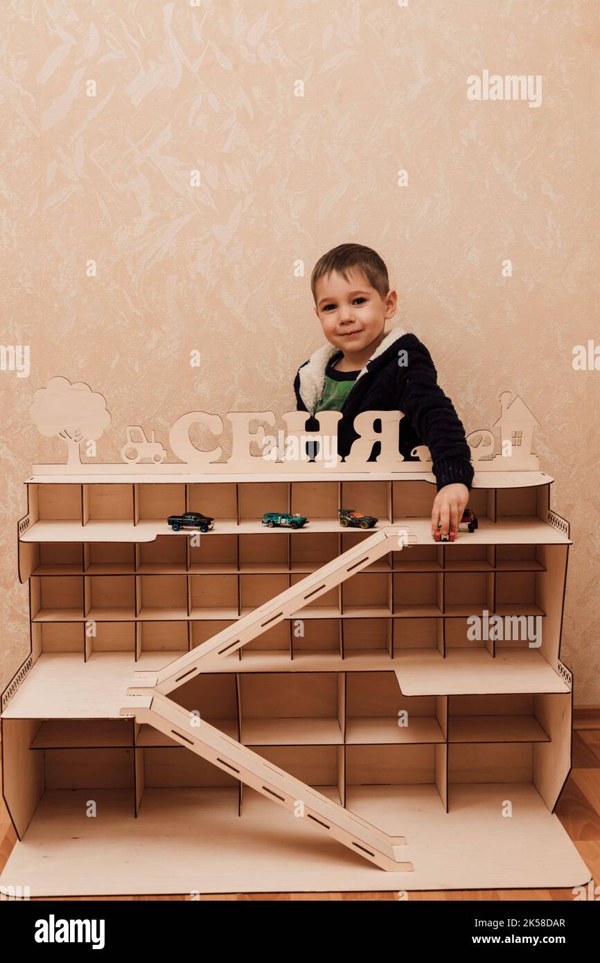 A little boy plays with cars in a wooden large parking lot Stock Photo ...