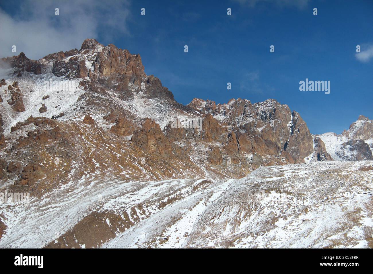 Red snow-capped rocky mountains, sky in clouds Stock Photo - Alamy