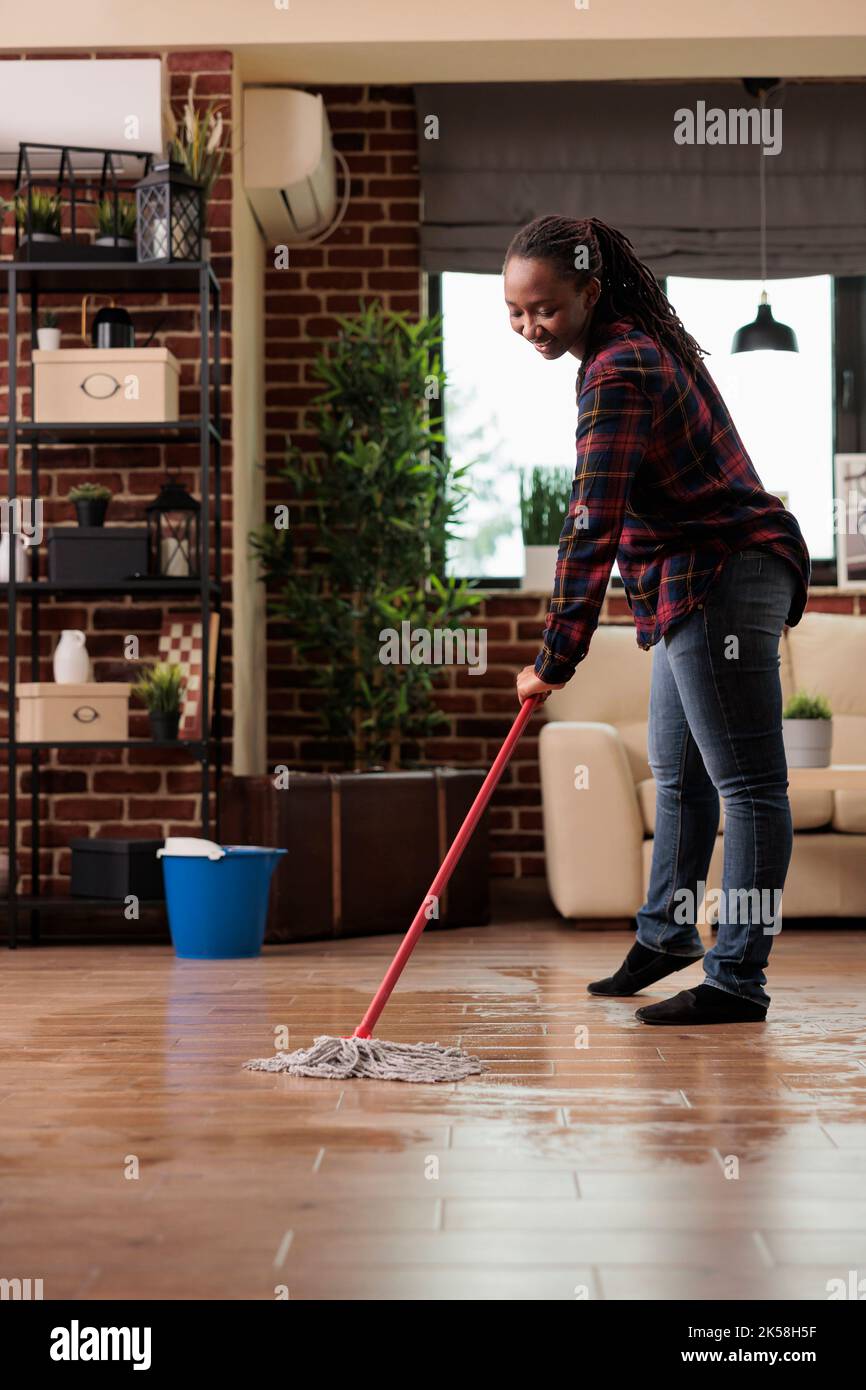 African american woman mopping the floor at home, doing housework on ...