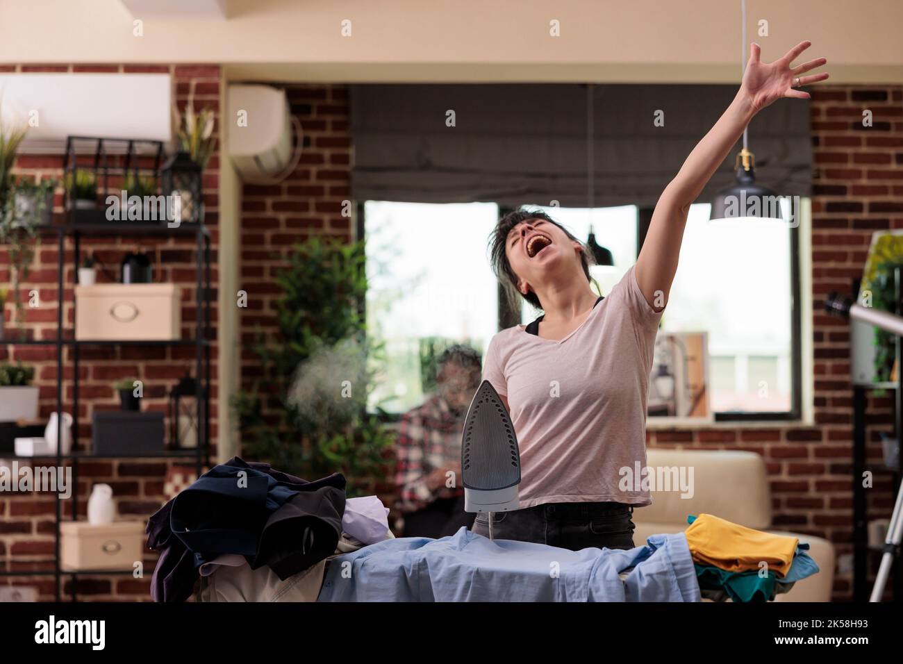Housewife singing while ironing clothes with emotion and good vibes ...