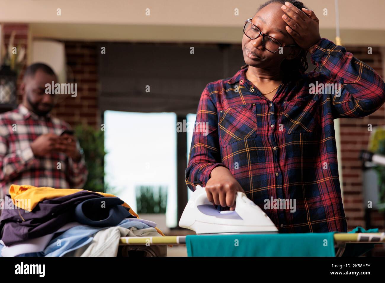 Stressed african american woman does housework without help from ...