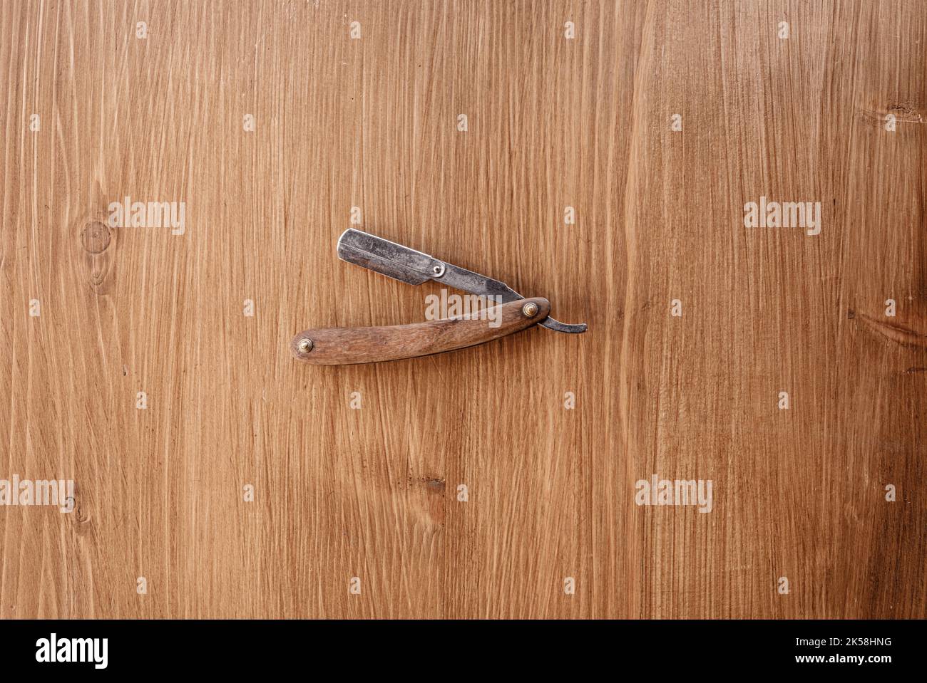 Vintage straight razor with wooden handle isolated on wooden background ...