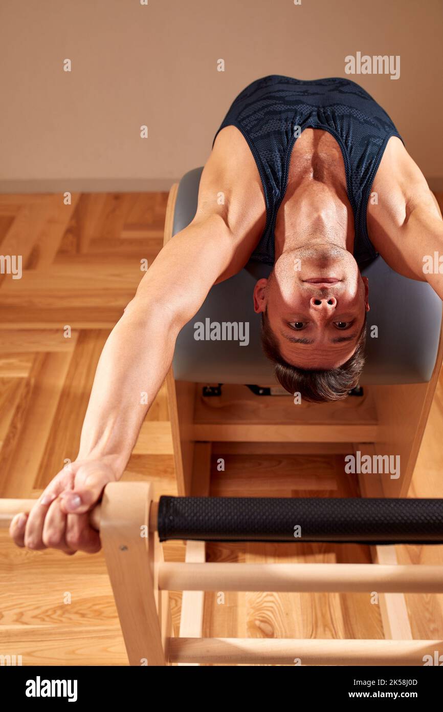Handsome pilates male instructor performing stretching balance fitness ...