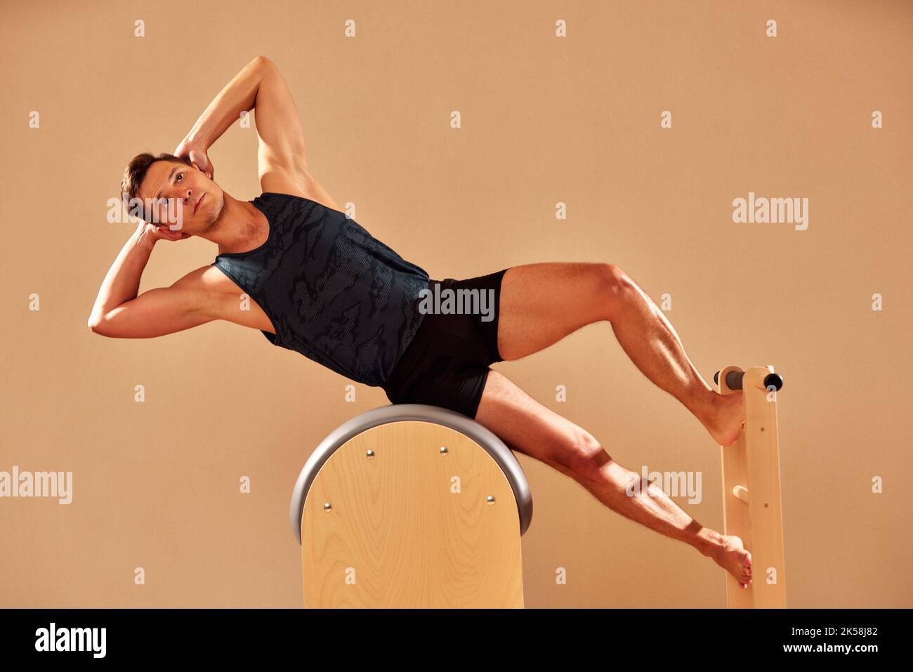 Handsome pilates male instructor performing stretching balance fitness ...
