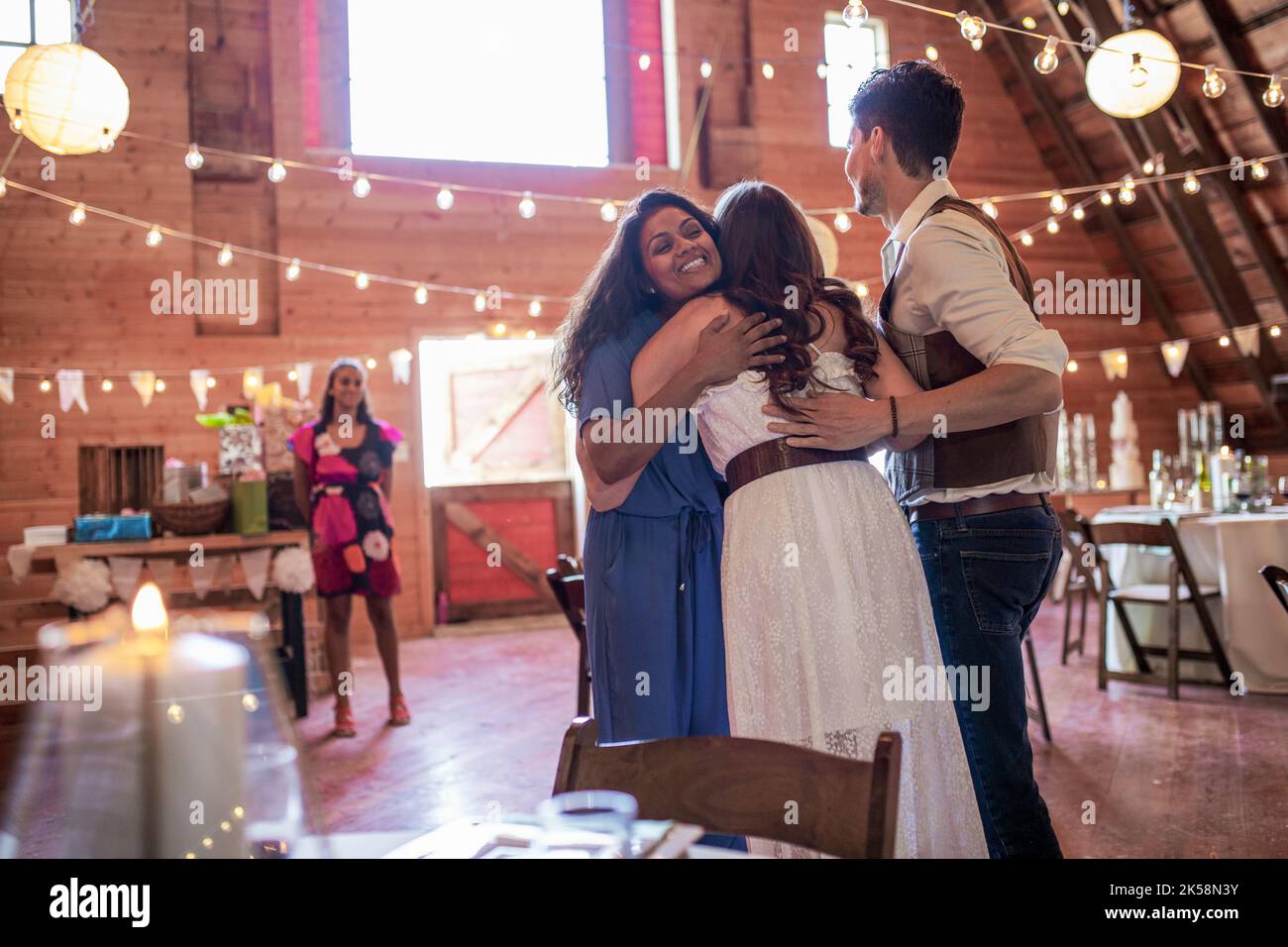 Happy wedding guest hugging bride and groom at wedding reception Stock ...