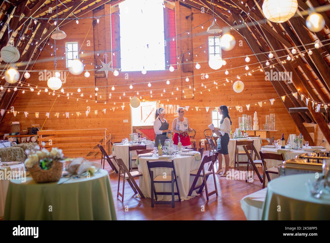 Wedding planner and workers preparing for wedding reception in barn ...