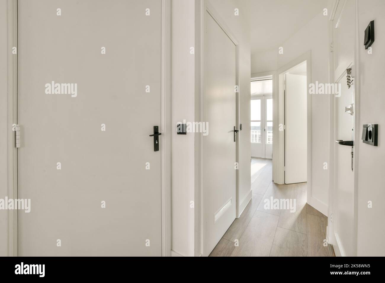 Light narrow hallway with many doors in white walls and glowing lamp ...