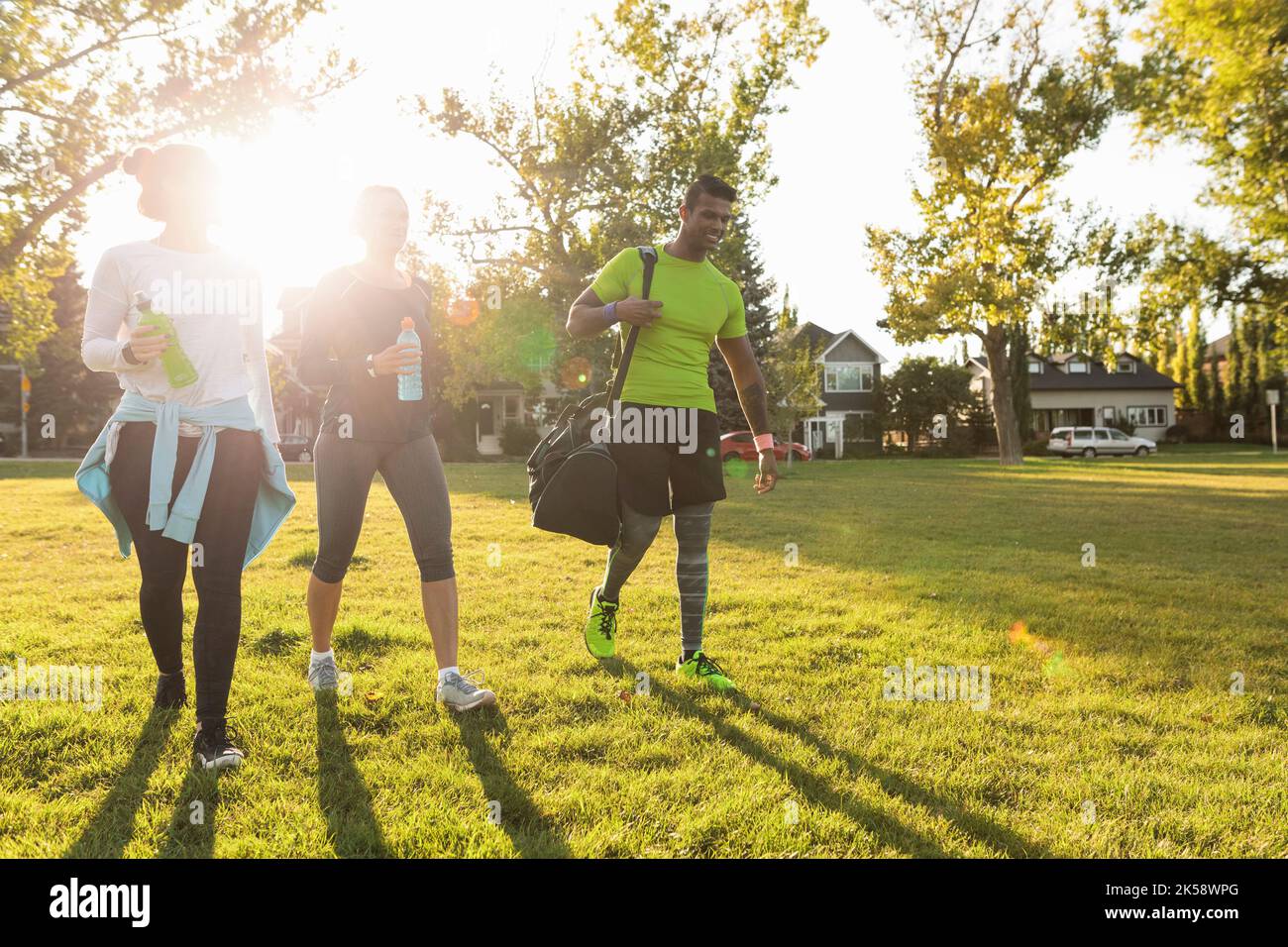 Three people walking in park after running club Stock Photo - Alamy