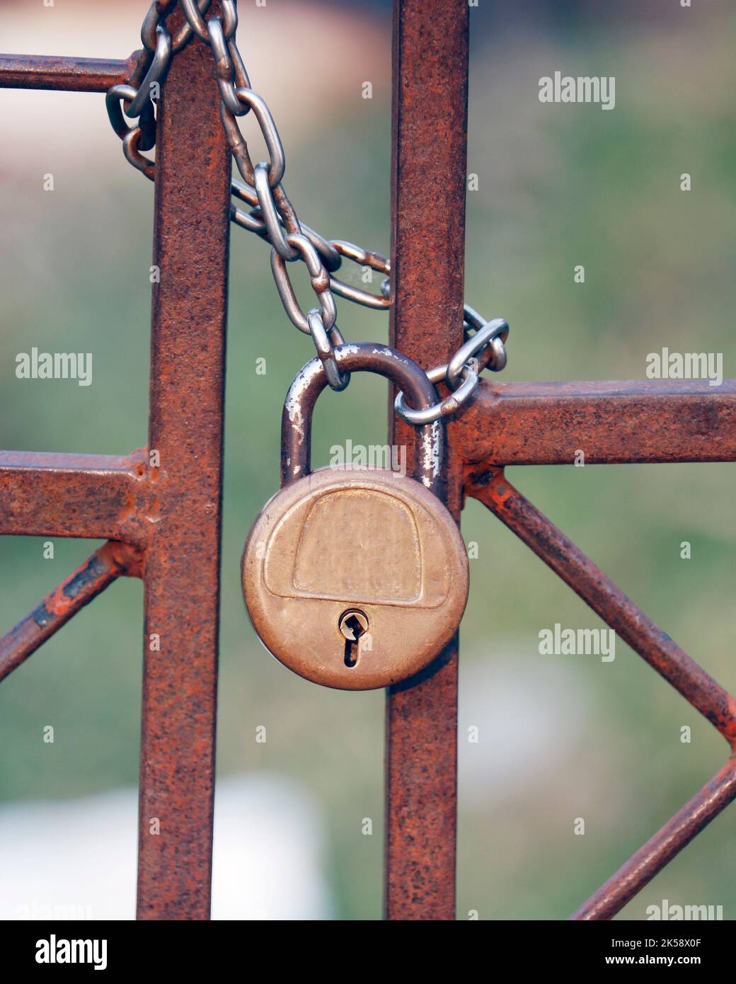 padlock and strong steel chain wrapped around the metal entrance gate ...