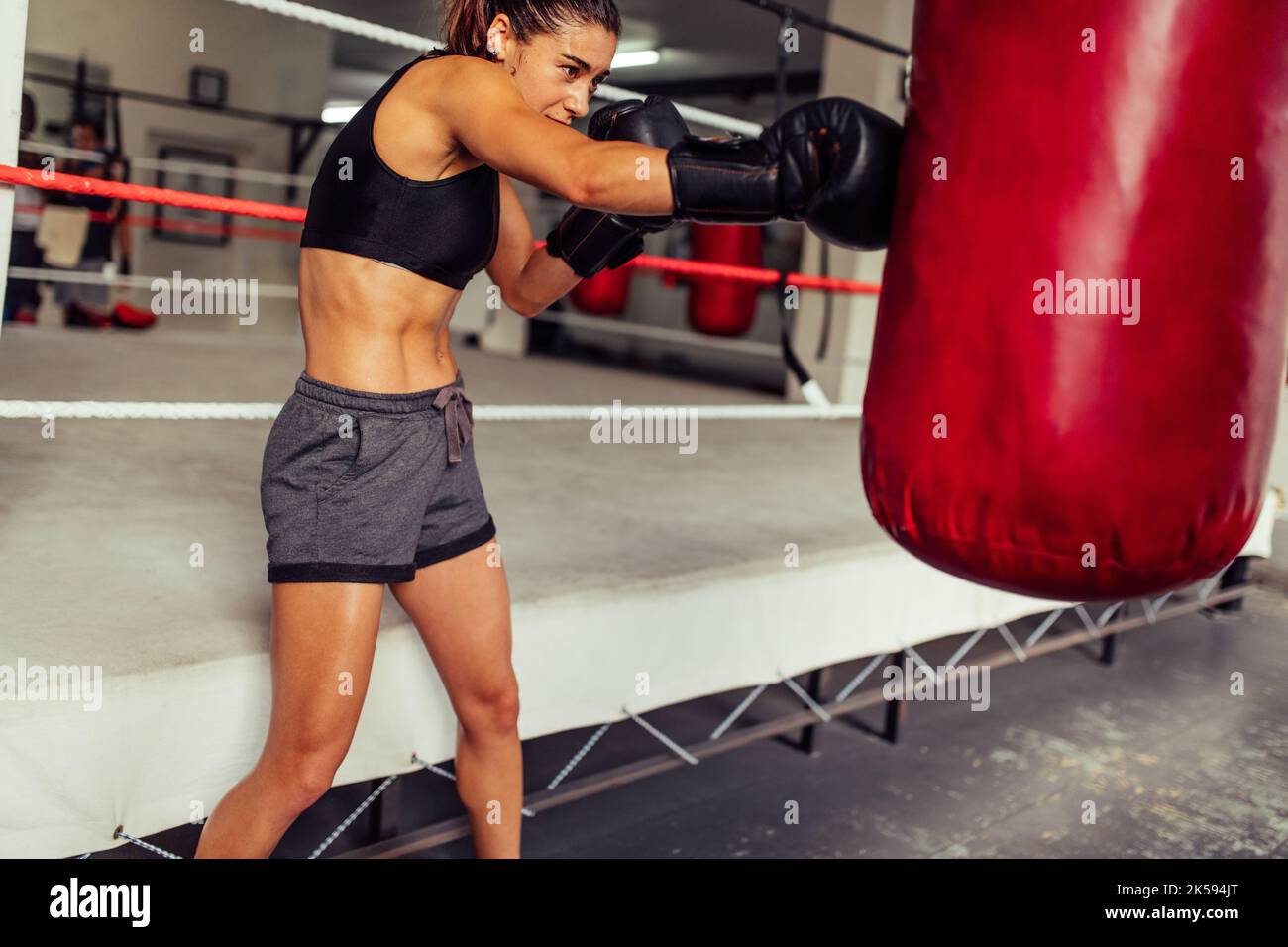 Female boxer punching a red bag while working out at the gym. Sporty ...