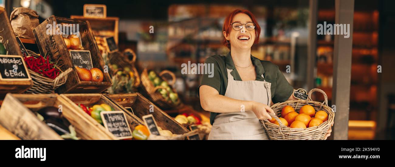 Successful grocery store owner smiling at the camera while holding a ...