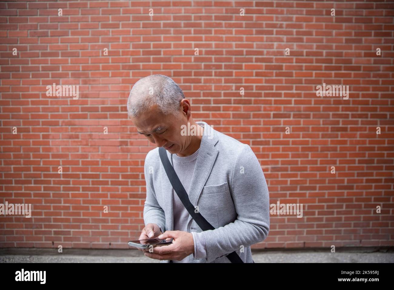 Man using smart phone in front of brick wall Stock Photo - Alamy