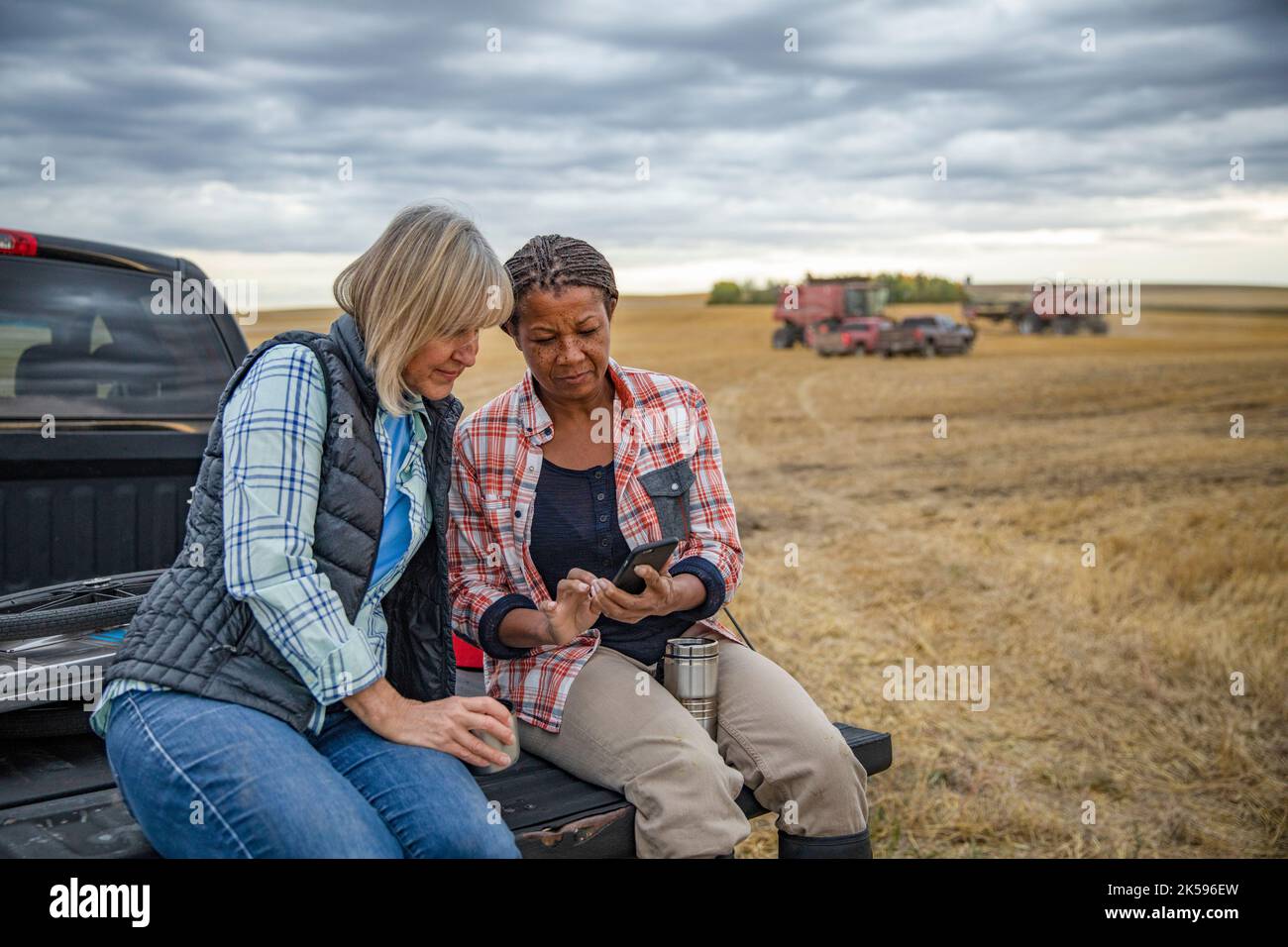 Female farmers using smart phone at pickup truck in rural field Stock ...