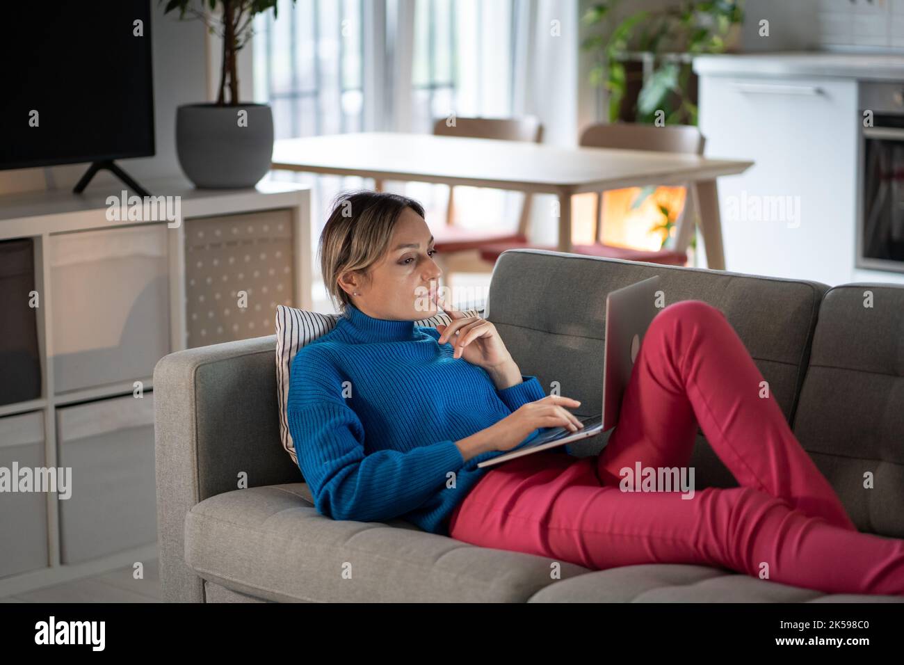 Focused attractive Caucasian woman writer with laptop writes book lies ...