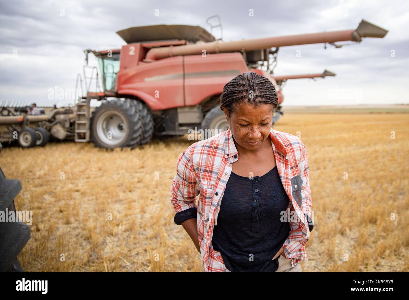Female farmer walking away from combine harvester in rural field Stock ...