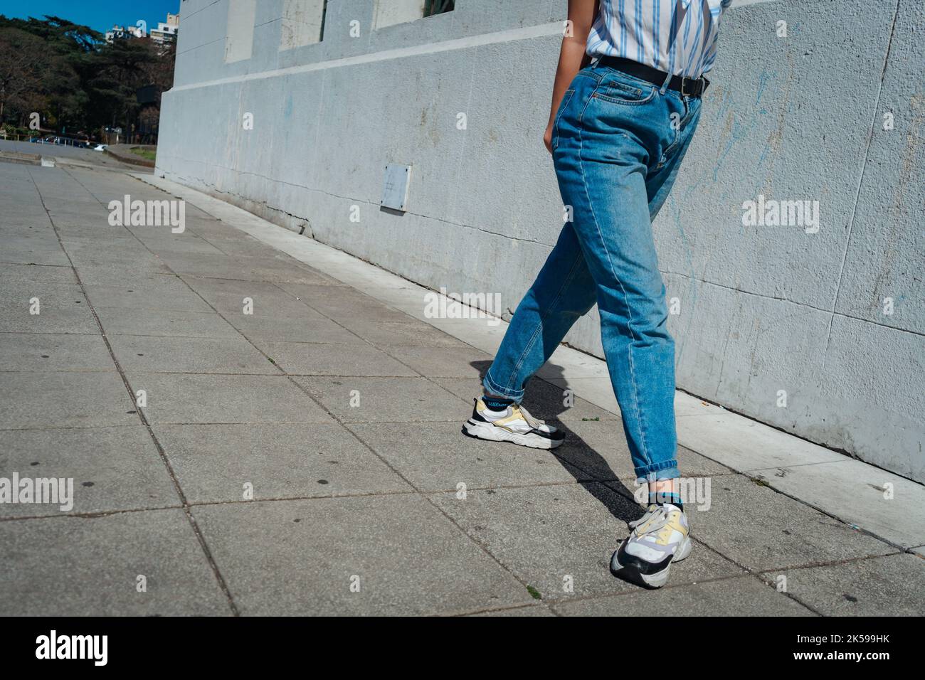 Close-up of a woman's legs walking down the street wearing jeans and ...