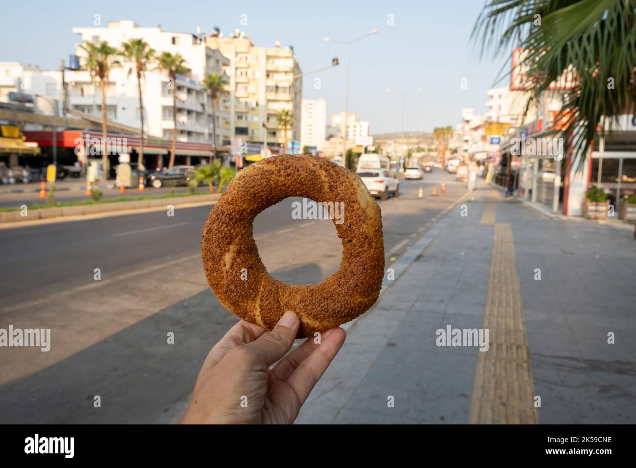 Hand holds traditional Turkish simit on typical resort street Stock ...