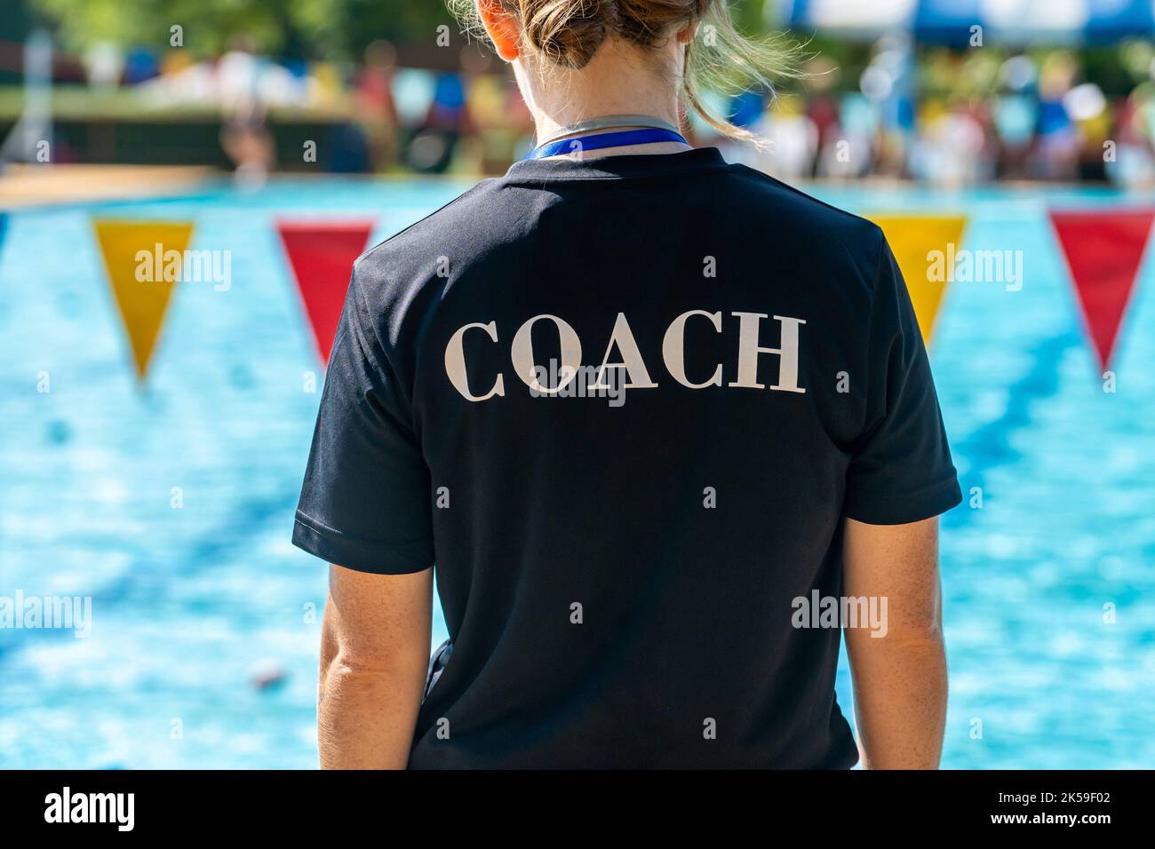 Back View Of Swimming Coaches Wearing Coach Shirt Working At An