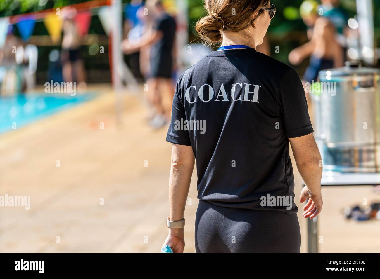 Back View Of Swimming Coaches Wearing Coach Shirt Working At An