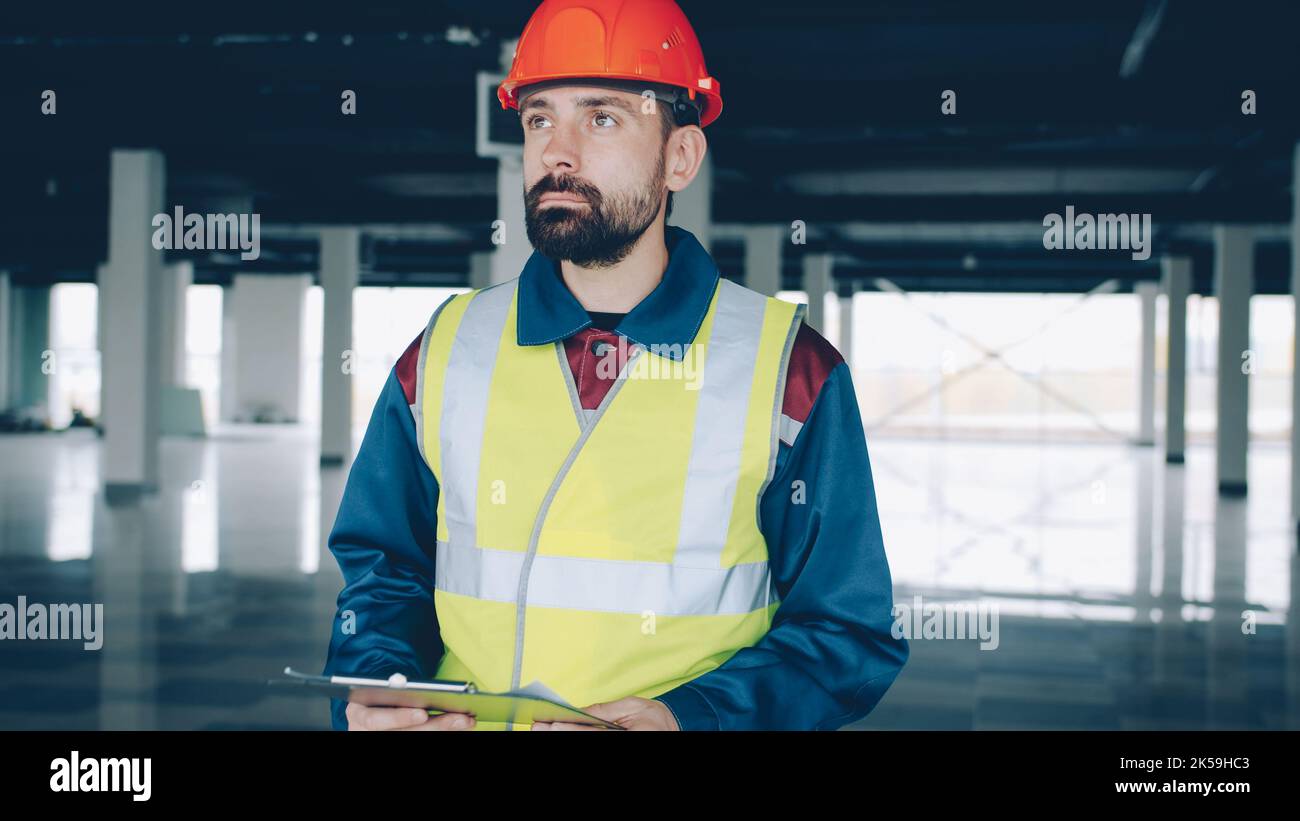 Construction inspector wearing uniform is checking papers and studying ...
