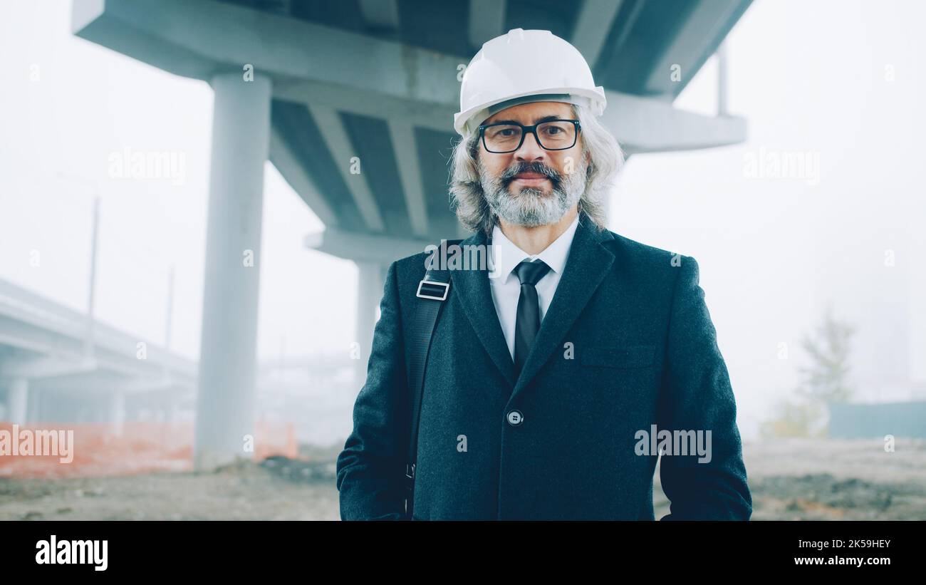 Portrait of successful man architect standing outside in construction ...