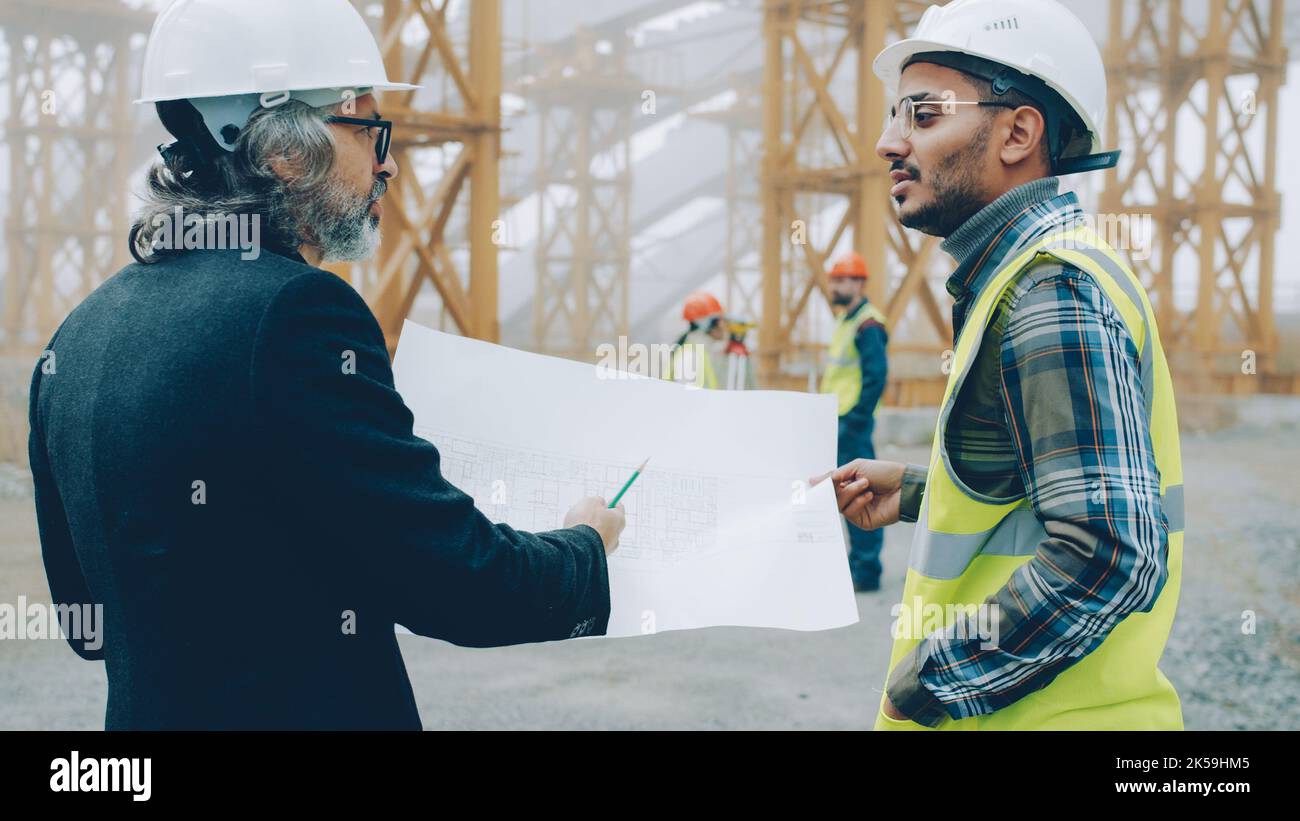 Back view of engineers discussing construction project looking at ...