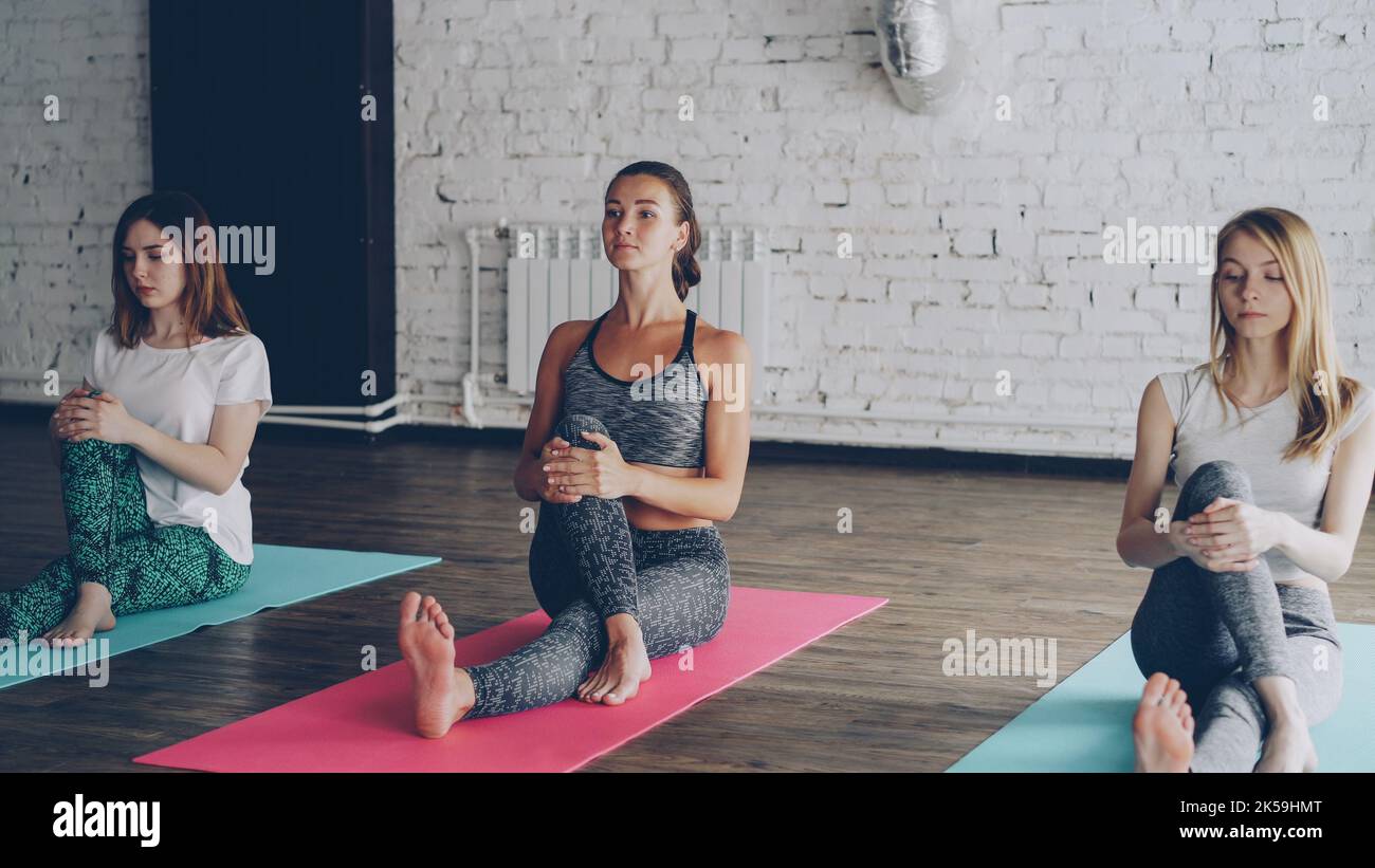 Female starting yoga students are sitting on bright mats and doing ...