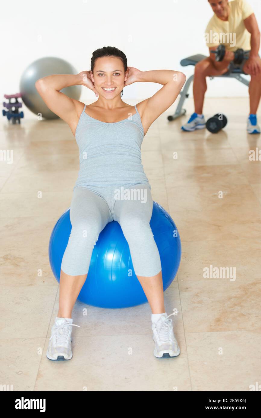 Strengthening her core muscles. A young woman doing sit-ups on a yoga ...