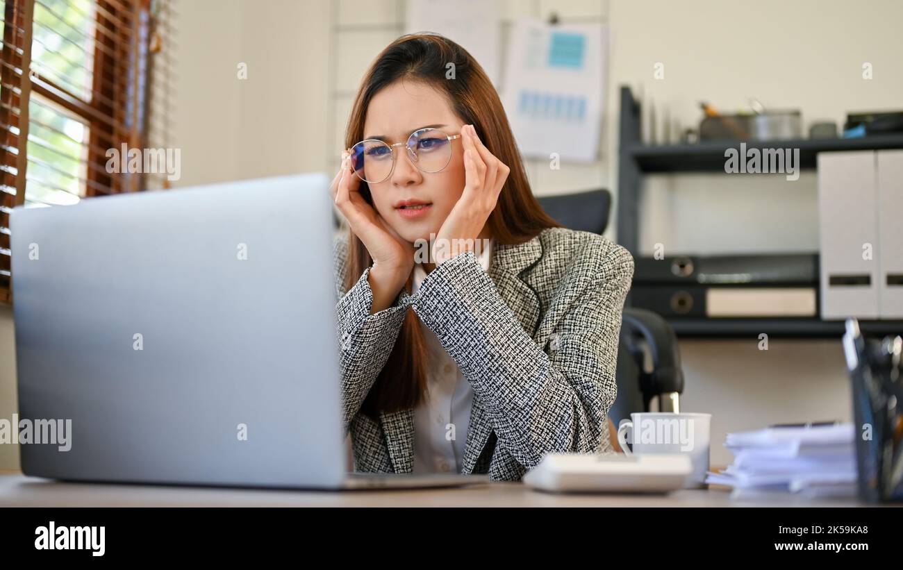 Thoughtful and confused millennial Asian businesswoman or female boss ...