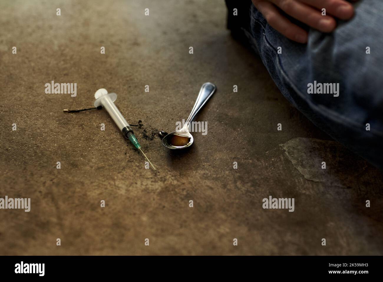 Addicts tools. Closeup shot of a person sitting next to a syringe and ...