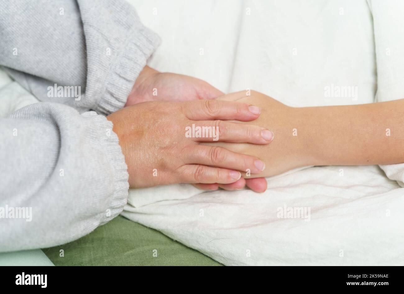 Mom holds the hand of a sick teenager girl, strokes her hand ...
