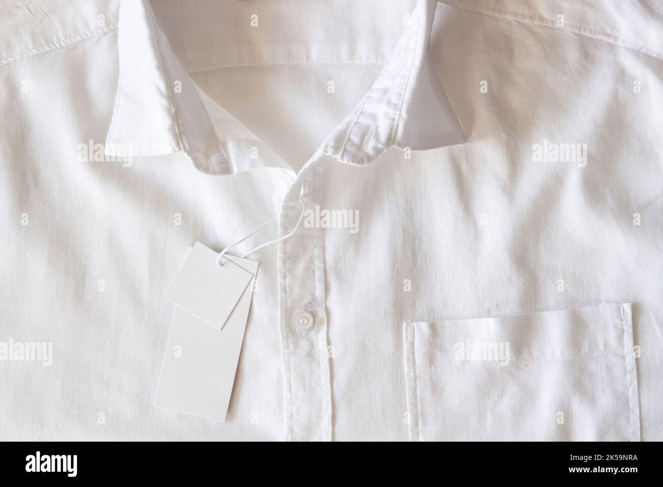 Blank price label tag paper card on white natural linen shirt. Clothes ...