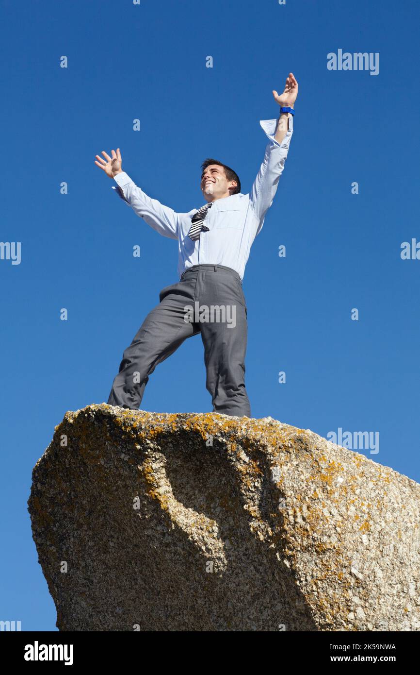 Reaching the pinnacles of success. A young businessman standing with ...